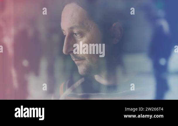 Adult caucasian sad man standing by the window of his living room and ...