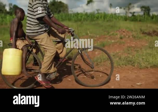 African man on push bike with a child holding a water container Stock ...