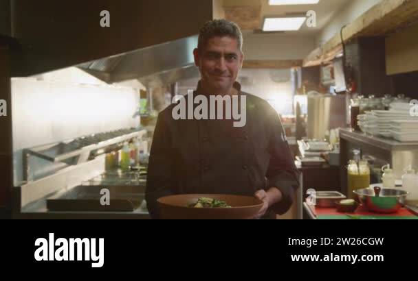 Portrait of a Caucasian male chef working in a busy restaurant kitchen ...