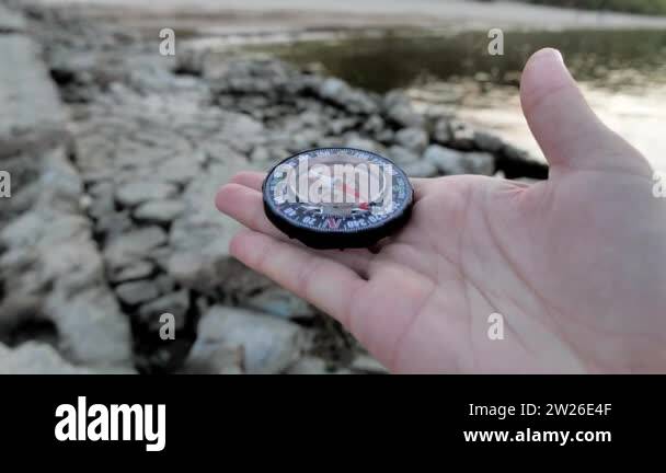Tourist compass on the hand using a compass on the stone beach with ...