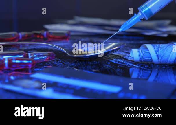 Addict is filling syringe with heroin from spoon, close up. Man is ...