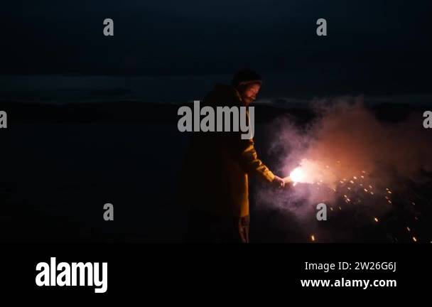 man raincoat,waving red smoke signal,light, lake mountains.traveler ...