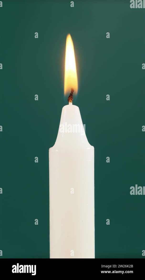 A Single Candle is Lit on a Green Background. Lighting. Candle Flame ...