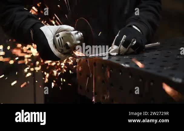 A welder, using an angle grinder, produces custom clamps for working on ...