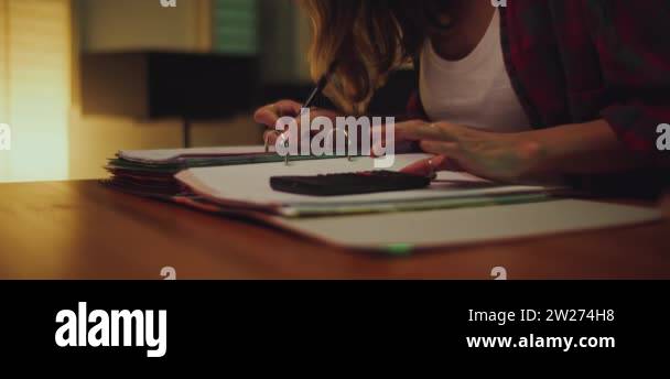 Young woman student studying at home in the evening, writing notes and ...