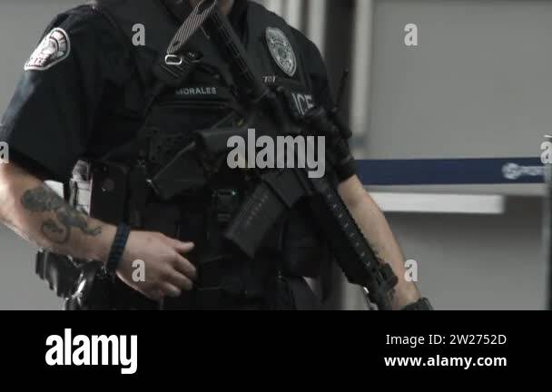 Happy police officer with large machine gun dances in front of crowd at ...