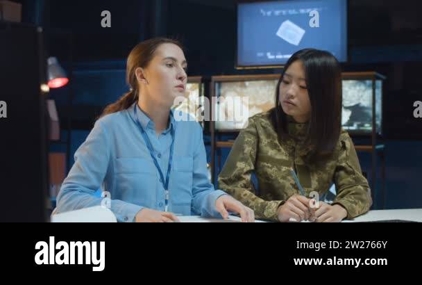 Female Caucasian office worker and soldier sitting together at desk in ...