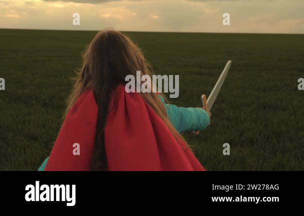 girl in a red cloak runs with swords in his hand across field playing ...