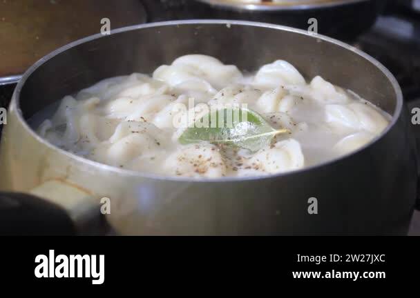 meat dumplings are cooked in boiling water in the kitchen. the chef is ...