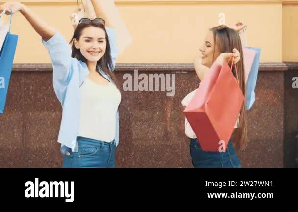 Two happy girls with shopping bags are boasting with purchses and ...