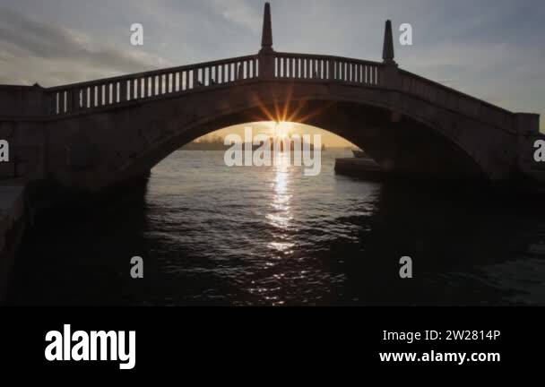 Glimpse under the vault of a bridge of the sun rays at sunset behind a ...
