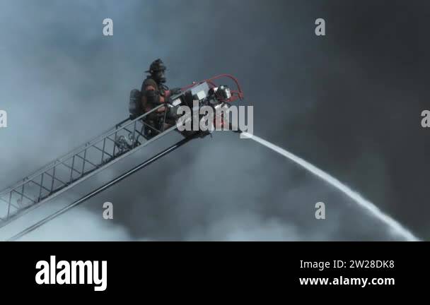 Firefighter battles fire below from firetruck's ladder but the smoke ...