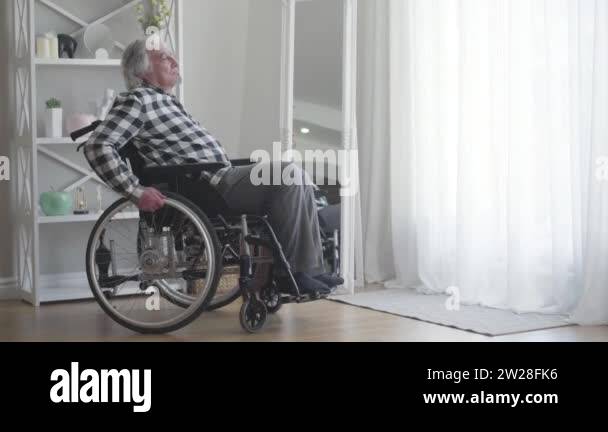 Portrait of sad old Caucasian disabled man turning wheelchair from ...