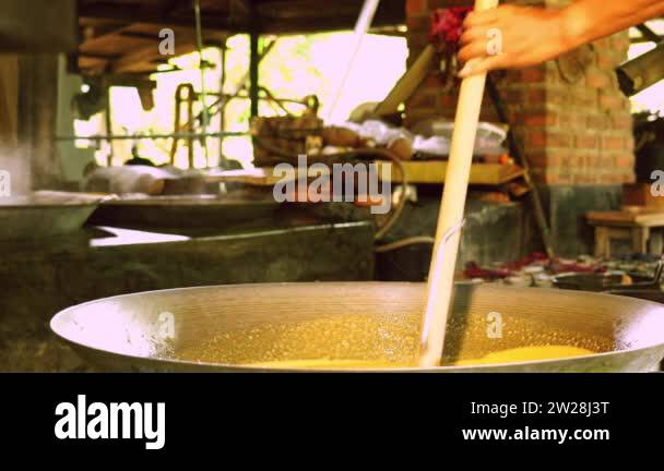 Coconut sugar production process. Farmer stir evaporated coconut sap in ...