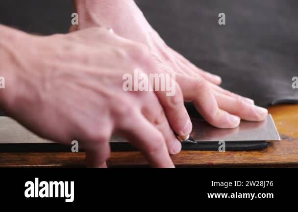 The tanner is cutting black leather sheet with a razor and metre Stock ...