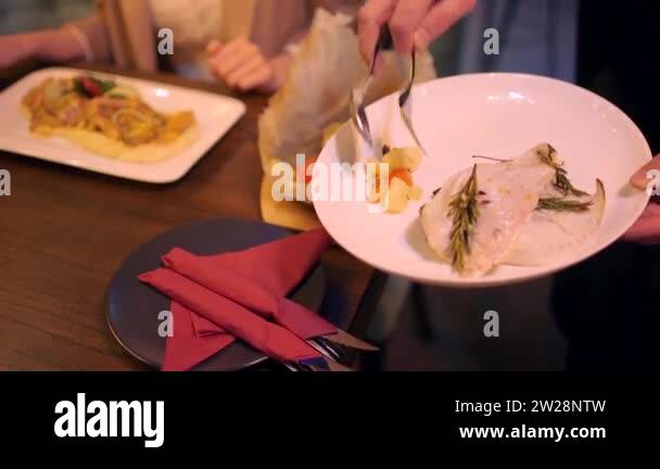 Cook serving fillets of gilt-head bream with side dish on the table in ...