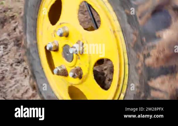 Yellow wheel of a tractor on a farm field. The motoblock is farm ...