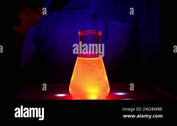 A scientist is mixing a red color solution on a magnetic stirrer UV ...