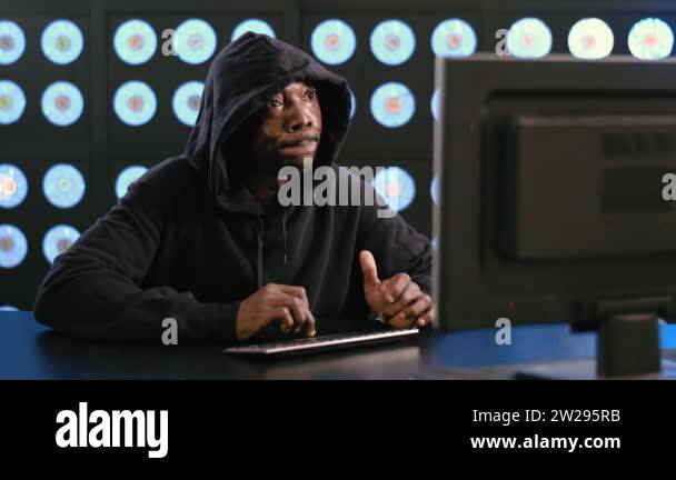 Worried-looking black mature man with sweating face is computer hacker ...