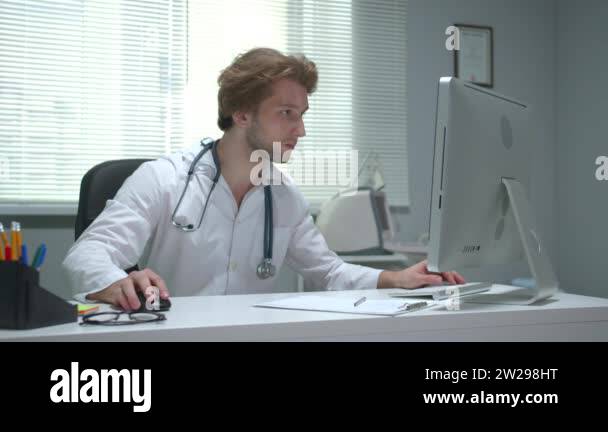 Doctor sit at a table in cabinet of hospital and type on keyboard Stock ...