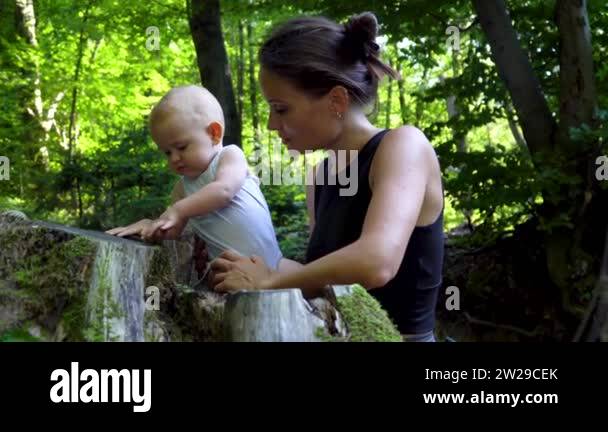 A cute baby with his beautiful mother exploring a stump in a forest. 4K ...