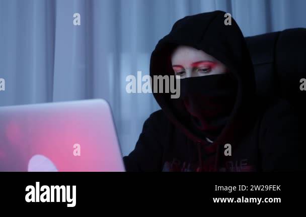 Close up of woman face in black mask and hood breaking password on ...