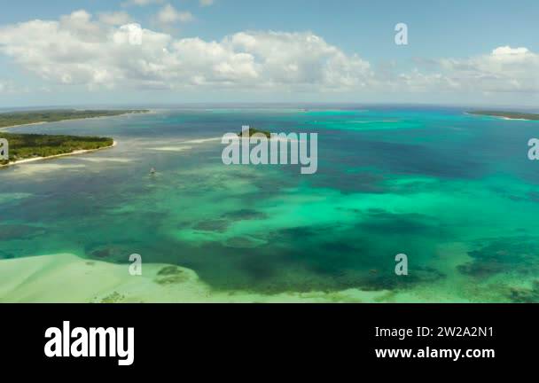 Tropical island covered with forest surrounded by an atoll and a coral ...