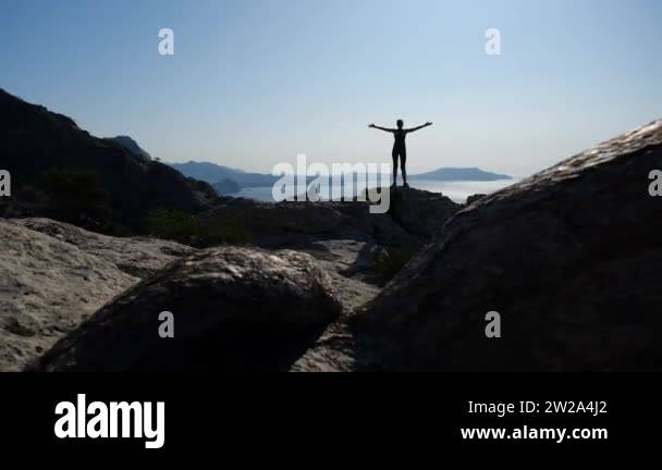 Slender girl with a sporty build. Slowly stretching her arms up while ...