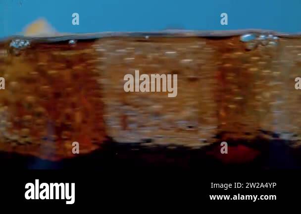 Spinning ice cubes in a carbonated drink close up. Cola fizzy drink ...