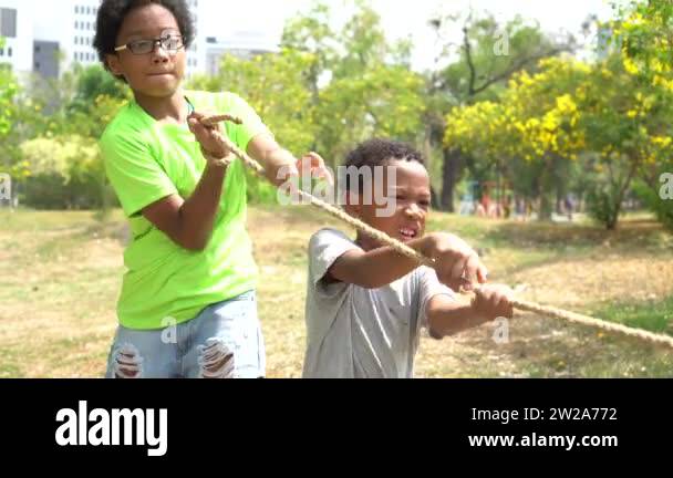 African American boy and girl pulling a rope together in tug of war ...