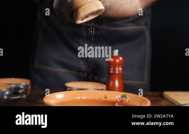 Close-up shot of chef using wooden mill to add some salt to dish, salt ...