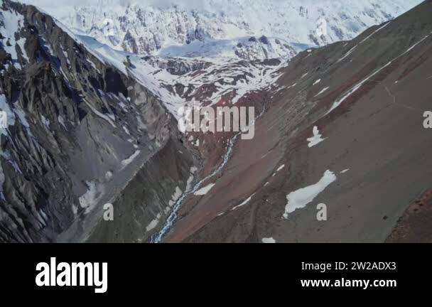 Atmospheric panoramic fly above river gorge near snowy mountain of ...