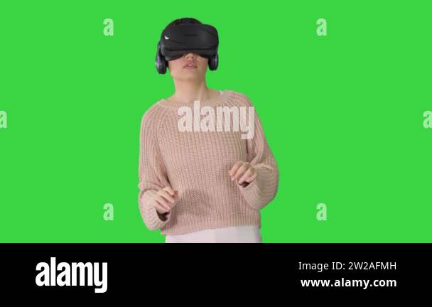 Cute young woman walking and using interactive VR headset on a Green ...