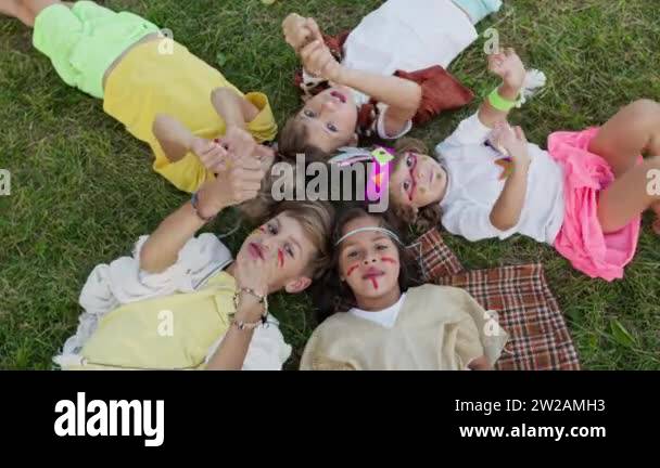 Five Children Lie On The Grass With Their Heads Facing Each Other ...