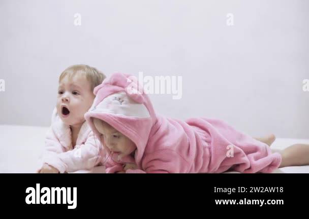 Two kids in bathrobes on a white background with wet hair after taking ...