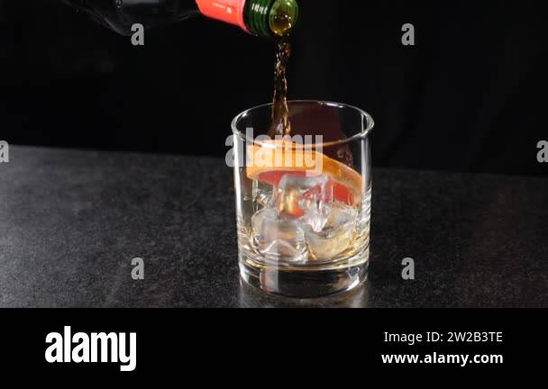 Slow motion of bartender pouring spirit out of bottle into glass. Close ...