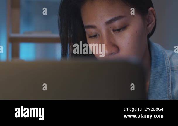 Millennial young Chinese businesswoman working late night stress out with project research ...