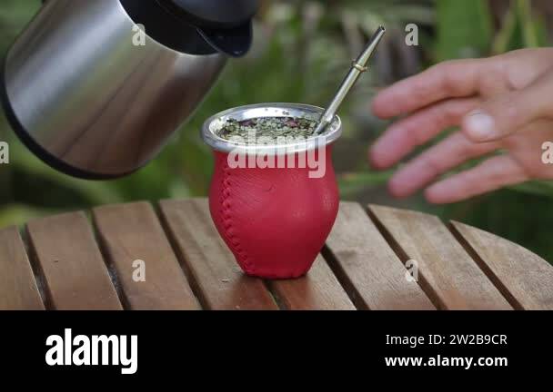 Man making yerba mate tea. Close up pouring hot water into traditional ...