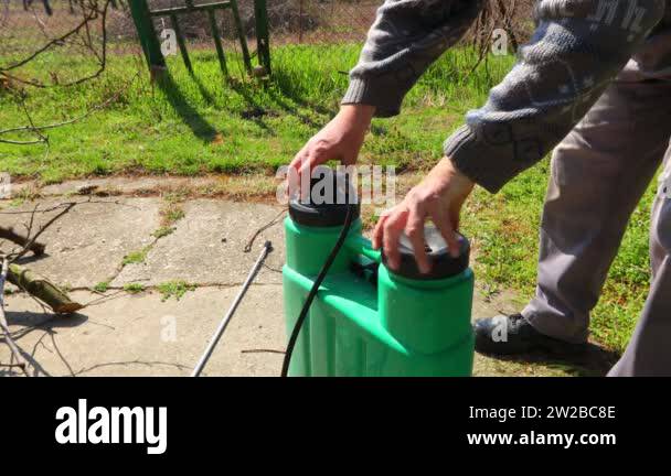 Farmer is preparing his plastic knapsack sprayer to spray fruit trees ...