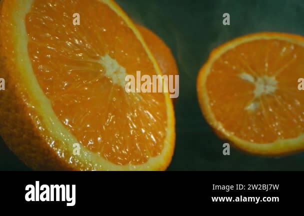 Zoom in macro still life footage of cut orange fruit in black ...