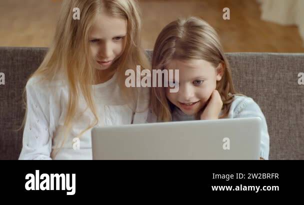 Children and technology. Two girls sisters sitting in living room ...