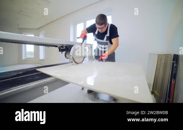 Tiler cutting tile on wet saw machine. The master cuts the tiles ...