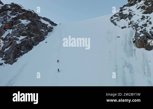 Alpinists climbs up over huge steep snow wall, obstacle on a way to ...