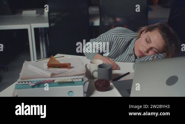 Sleepy young woman office worker lying on mess table with opened ...
