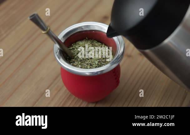 Man making yerba mate tea. Close up pouring hot water into traditional ...