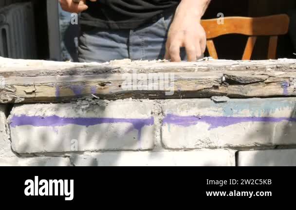 Mens hands dismantle the frames of an old rotten wooden window ...