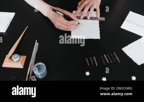 girl draws straight lines on a white sheet. Calligraphy, closeup top ...