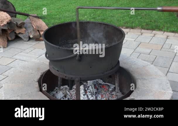 Mixing ground meat or puttens in an iron kettle over a wood fire Stock ...