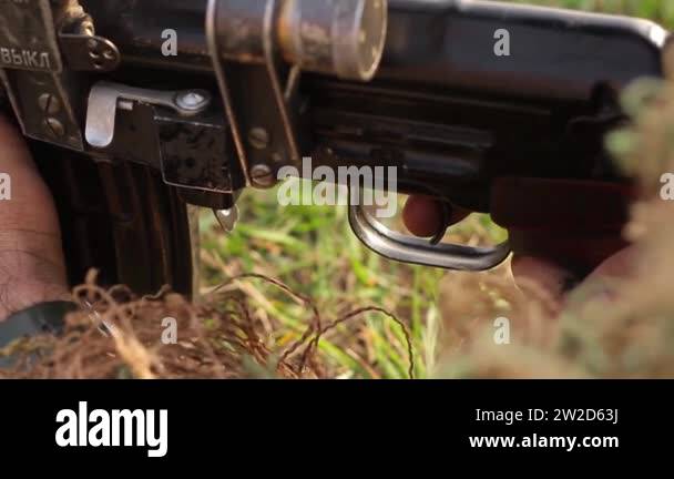 A sniper in a masking sniper suit, squeezes the handle of a sniper ...