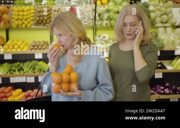 Beautiful senior Caucasian woman smelling fresh tasty tangerine as her ...